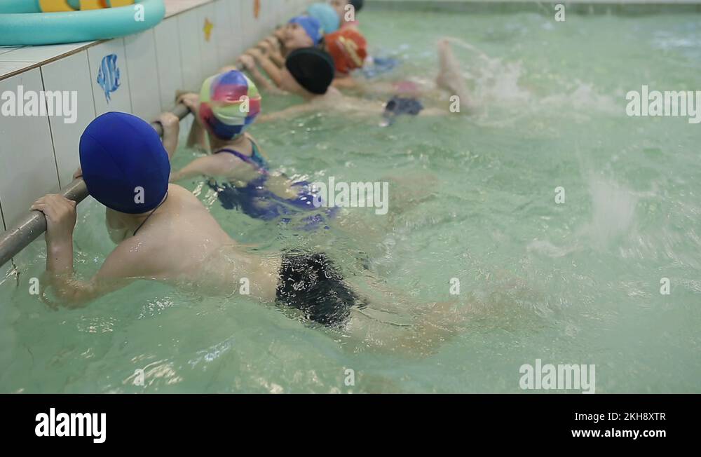 Children learning to swim in the pool. Children kick their feet in the ...