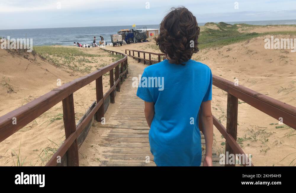 back of child walking towards beach using pathway Stock Video Footage ...