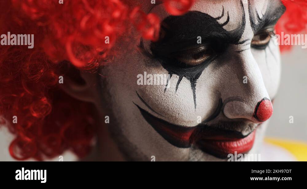 Scary clown viciously looks askance at camera with horror smile, face ...