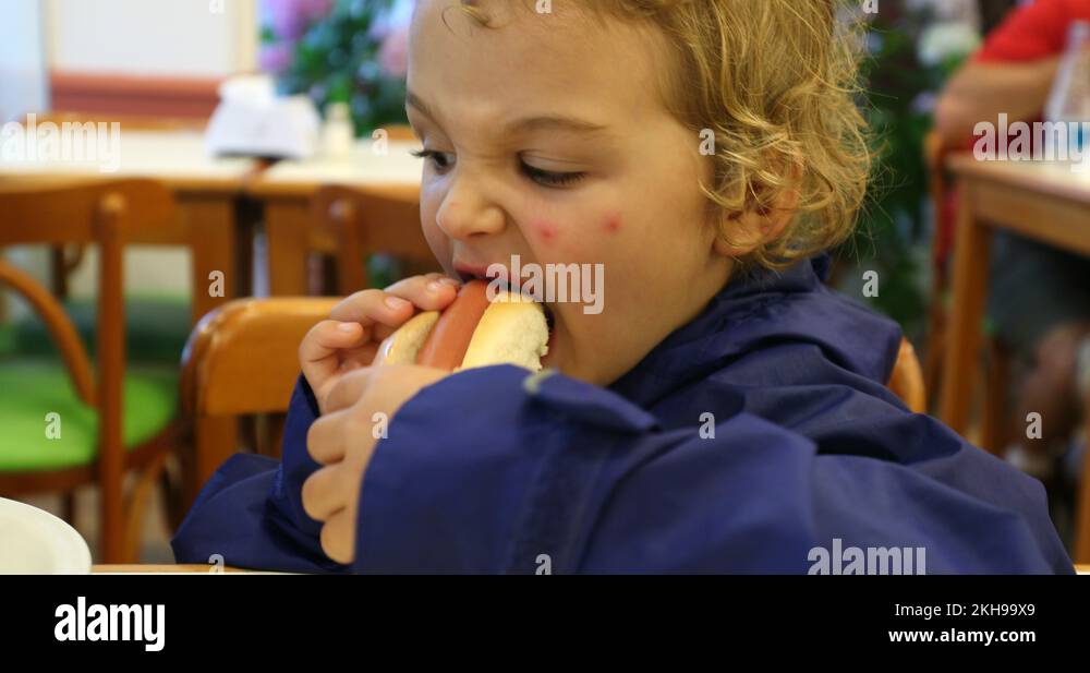 Child eating hot dog. Candid little boy taking a bite of hot dog Stock ...