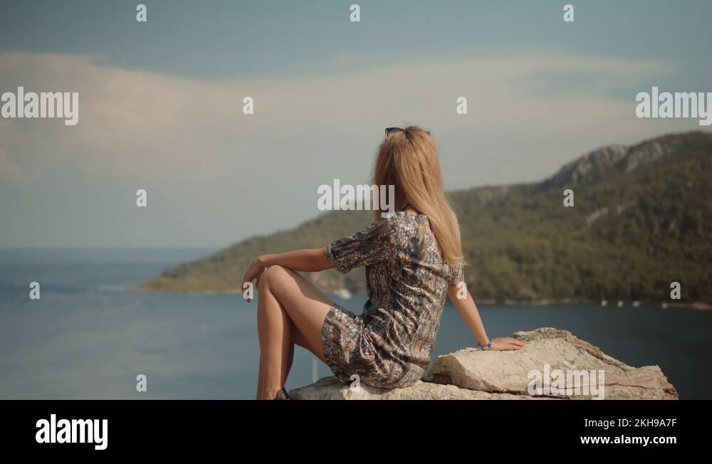 Girl Sitting On Cliff And Looks At Sea.Woman Sitting On Rock Stock ...