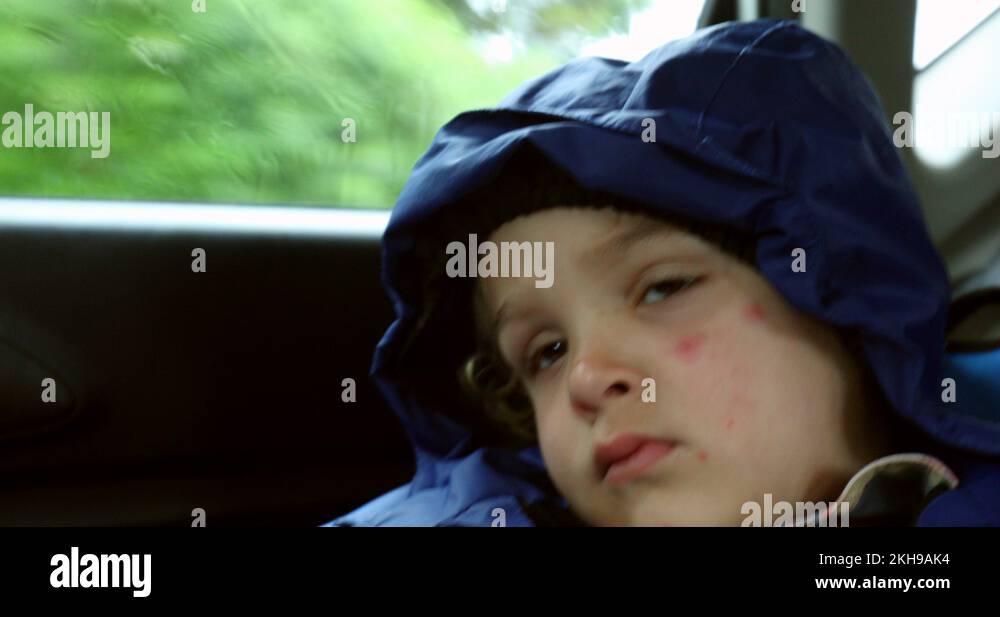 Sad looking little boy in the backseat of a car in rainy day. Toddler ...