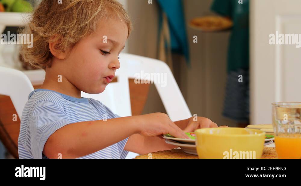 Child grabbing plate, breakfast morning setting, candid moment of boy ...