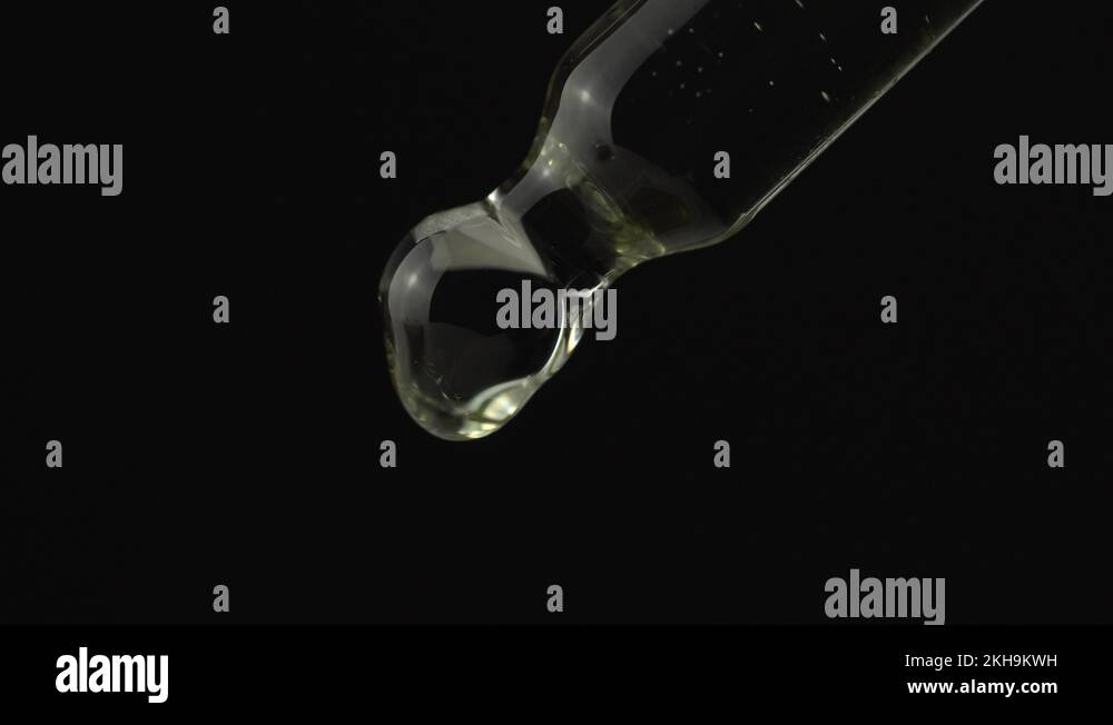 Liquid cosmetic oil dropping from laboratory glass pipette dropper ...