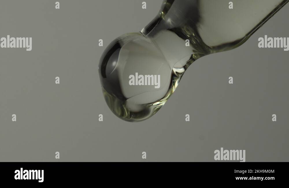 Liquid cosmetic oil dropping from laboratory glass pipette dropper ...