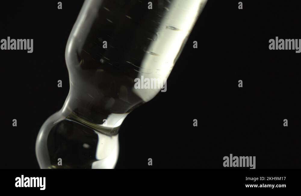 Liquid cosmetic oil dropping from laboratory glass pipette dropper ...