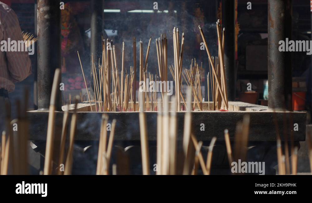 People praying and worshipping in Taoist temple interior bowing and ...