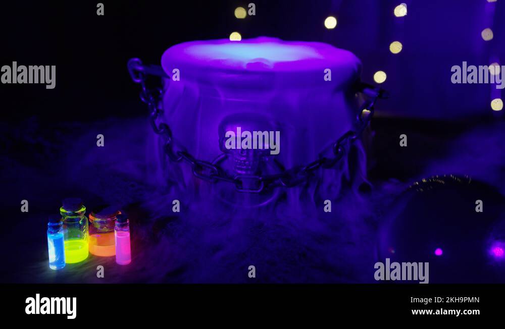 Bubbling smoking witch's cauldron with neon glowing vials and crystal ...