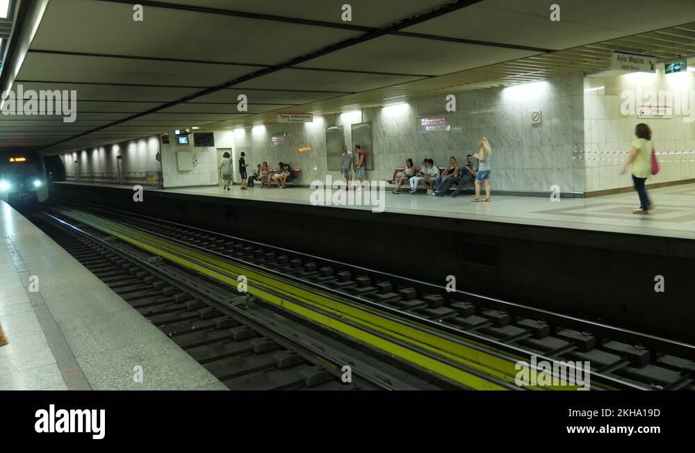 A modern train is moving and stopping in a Greek subway station in ...