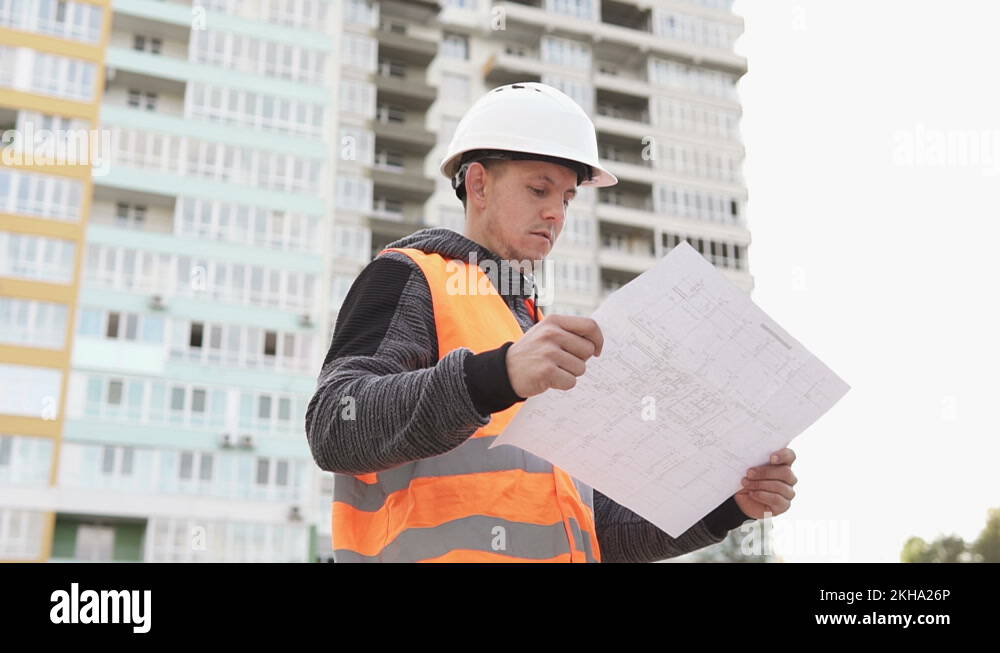 Civil engineer looking drawing of a tall building on the construction ...