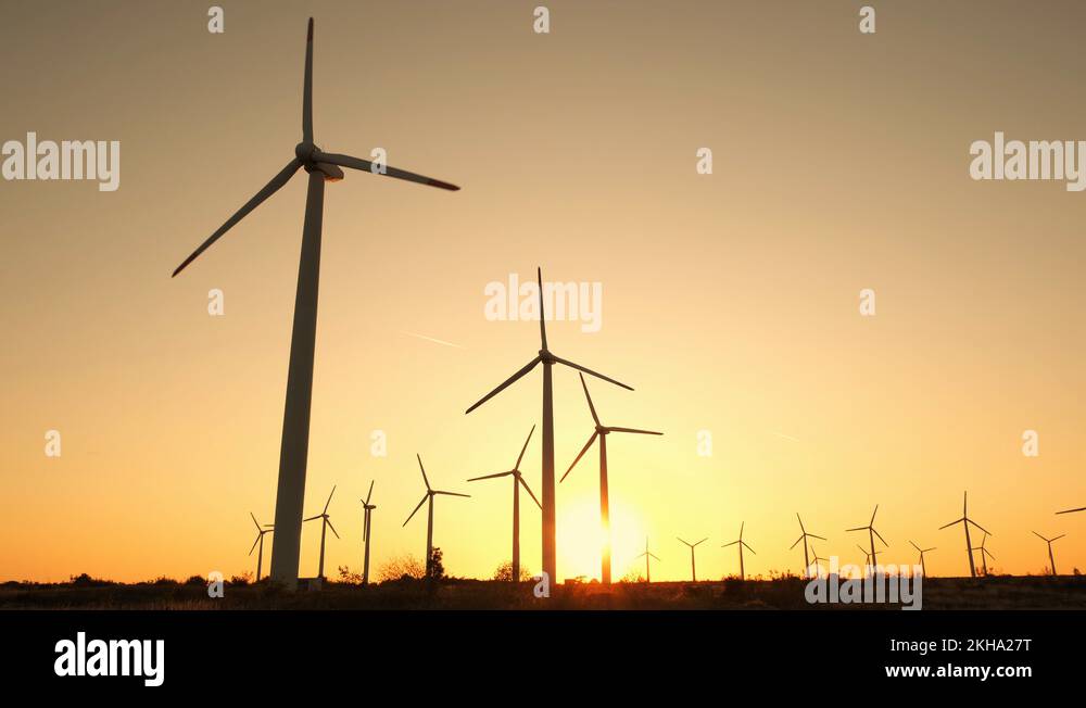 Motion the blades of a wind turbine in a field of orange sunset. Windy ...