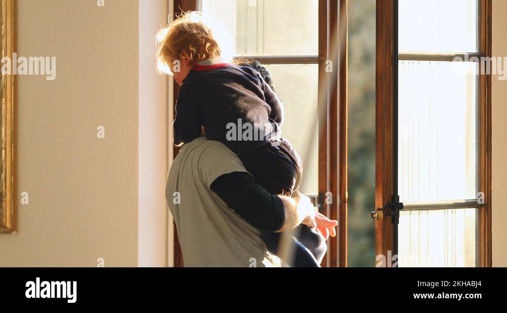 Dad closing home windows while carrying his baby son in his arms ...