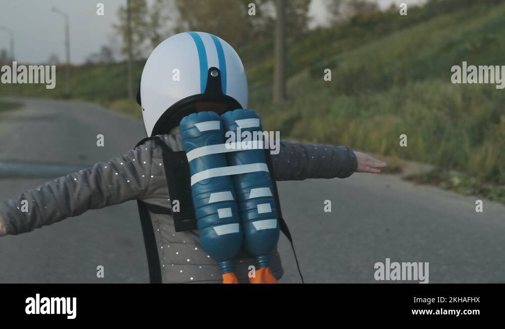 Cute girl running on rural road wearing helmet and jetpack, acting to ...