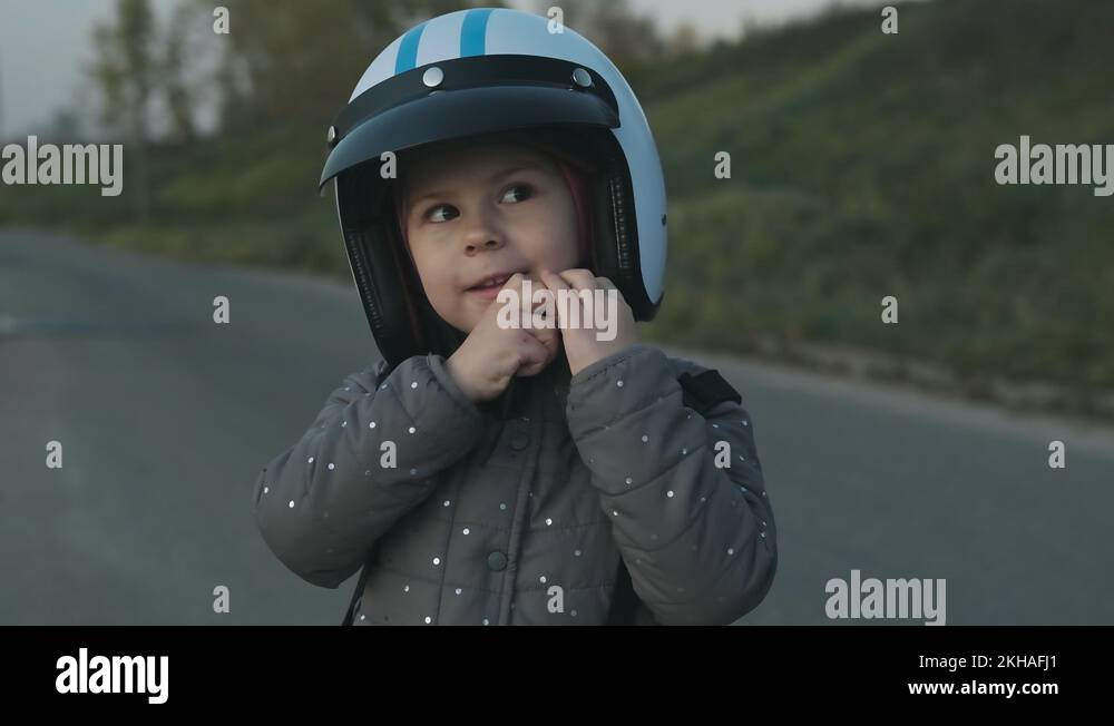 Little girl wearing helmet. Happy kid playing outdoors in slow motion ...