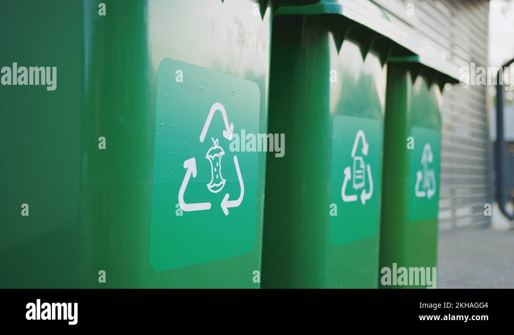 Green colored, plastic garbage bins, with different recycle logos on ...