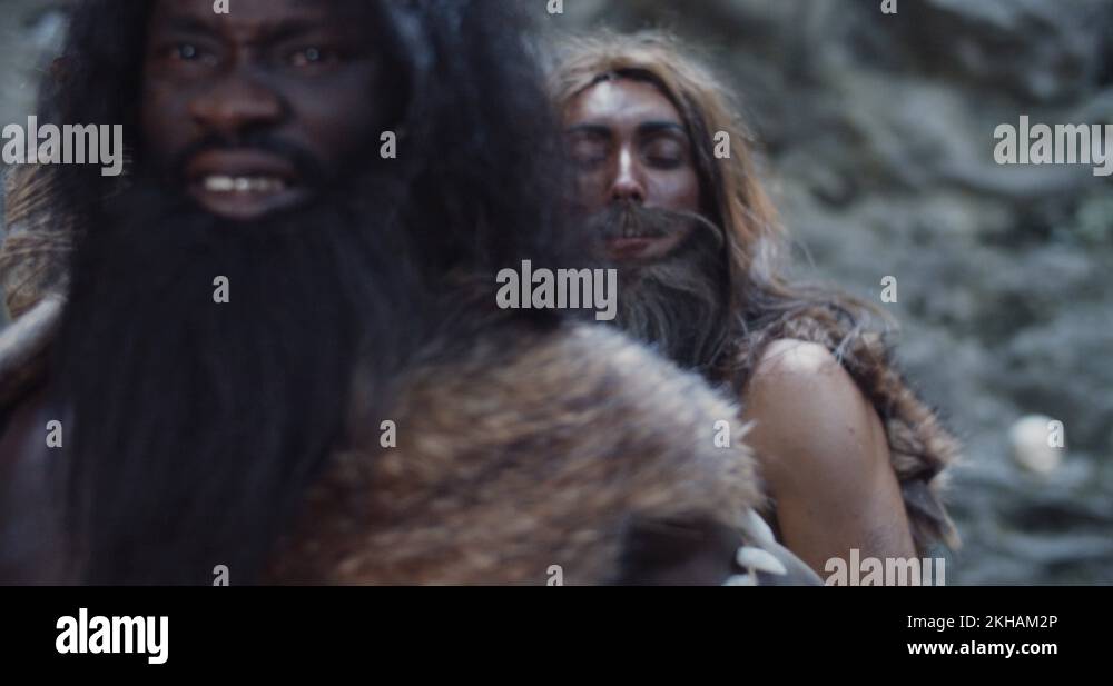 Tribe of cavemen neanderthals wearing animal skin holding weapon stand ...