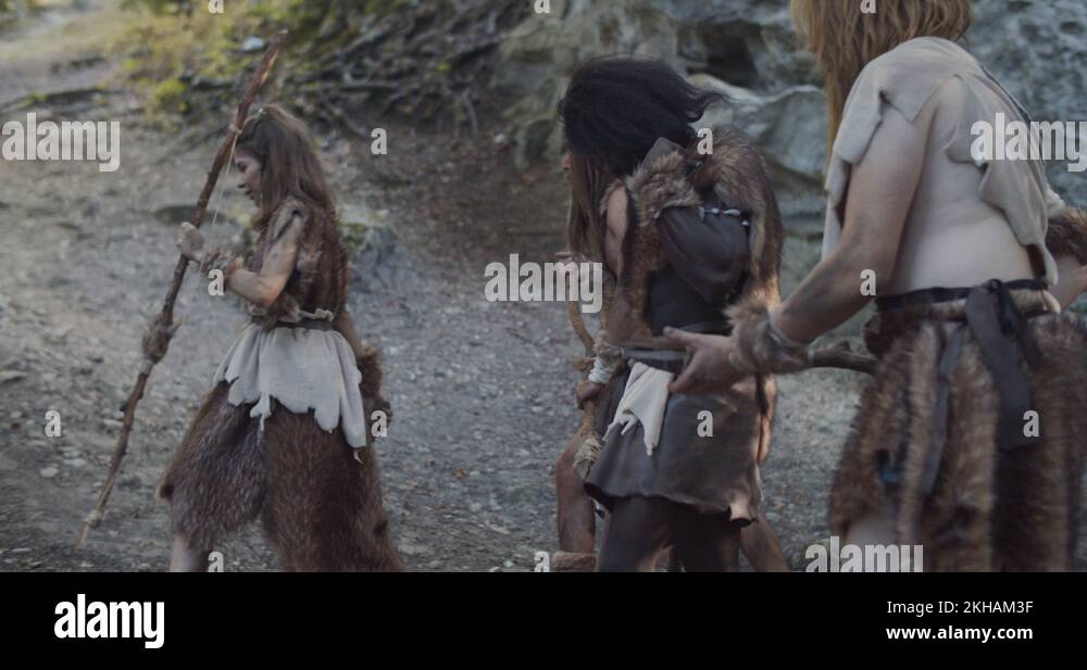 Slow motion tribe of cavemen neanderthals wearing animal skin holding ...
