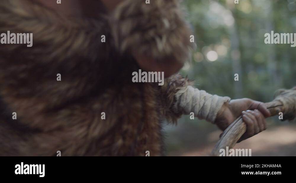 Hands holding weapon caveman wearing animal skin walk in prehistoric ...