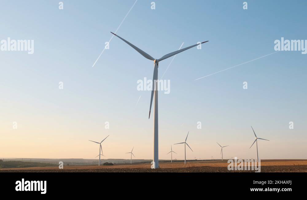 Rotating blades of a large wind turbine in a field background of orange ...
