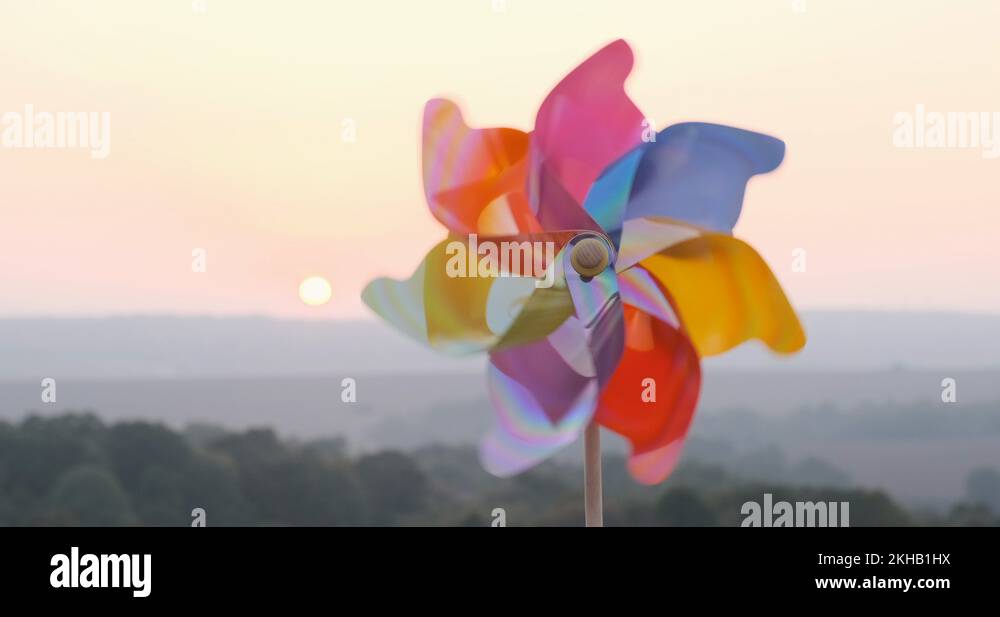 Rotating color plastic pinwheel, windmill blowing wind against sunset ...