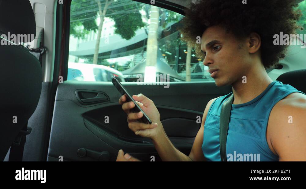 Young black african man using cellphone inside car riding in the ...