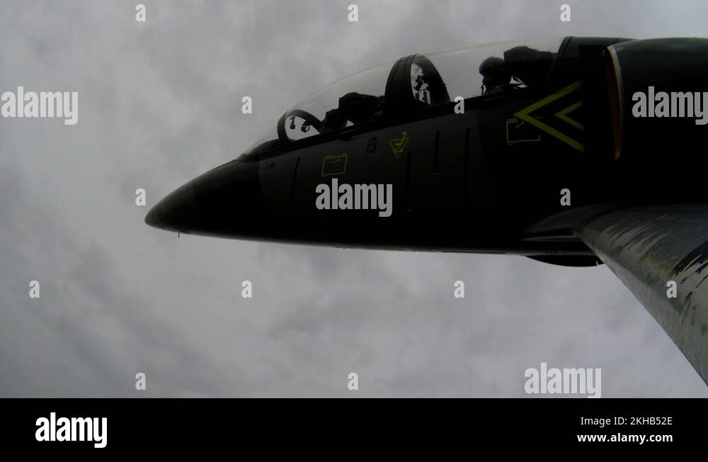Black silhouette of fighter plane high in the sky. View from left wing ...