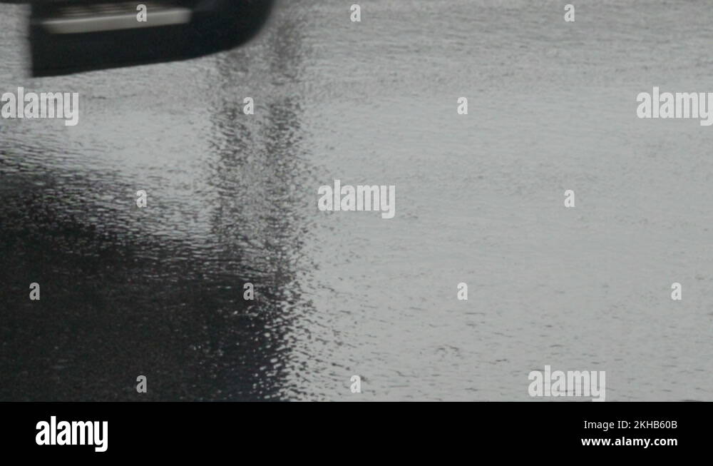 Splash by a car as it goes through flood water. Car driving on urban ...