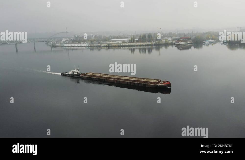 Big iron scow transporting sand through river in industrial downtown ...