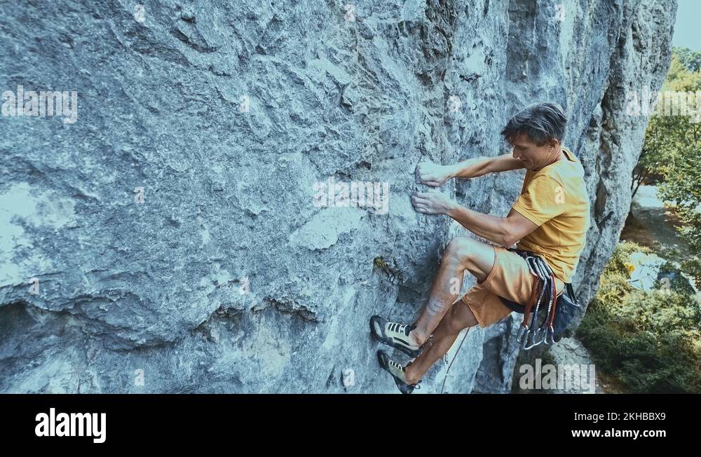 man rock climbing on tough sport route, rock climber makes a hard move ...
