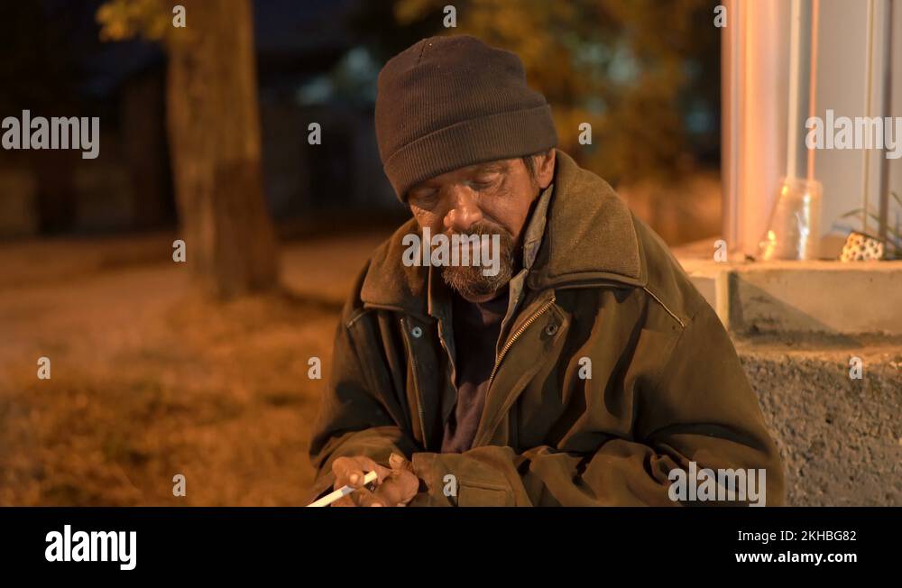 Homeless sick man smoking cigarette on the street at night Stock Video ...