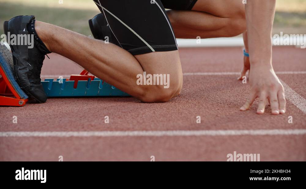 An athlete is getting ready for sprinting, putting feet in starting ...
