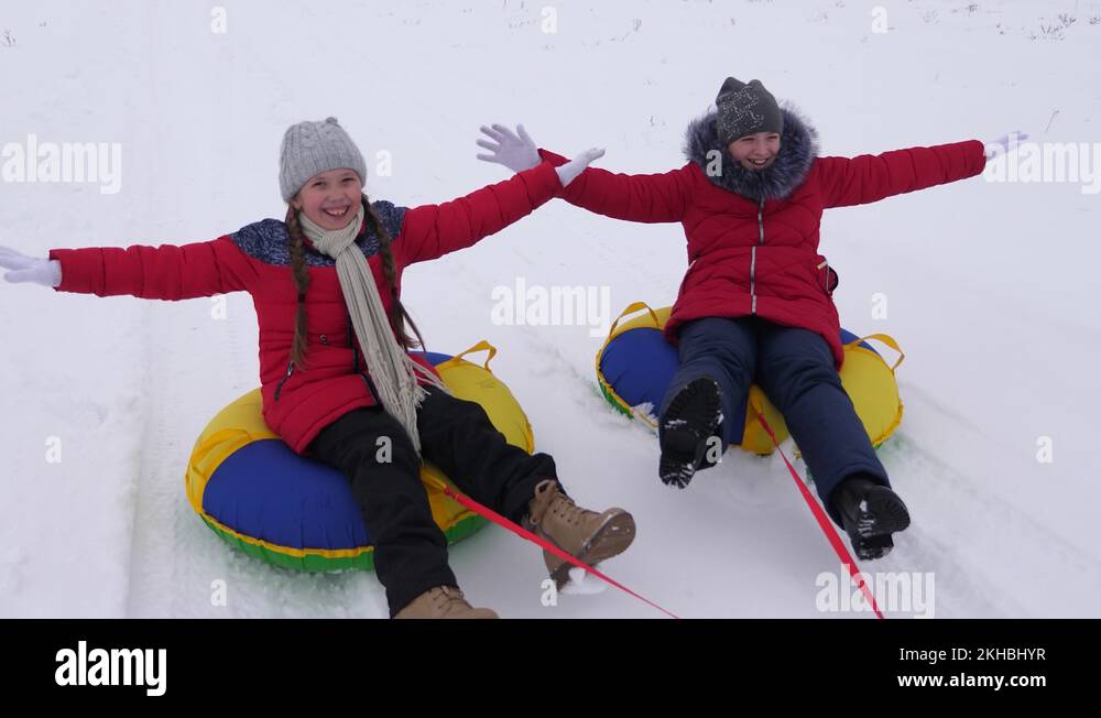Happy children sledding in snow in the winter and waving their hands ...