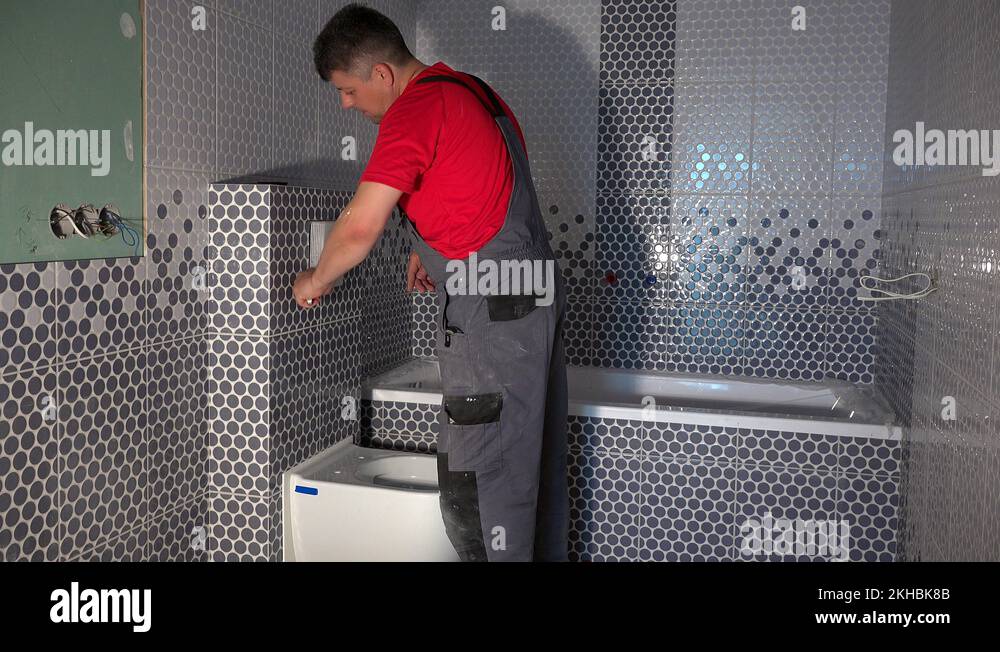 skilled worker man install toilet flush button in new modern bathroom ...
