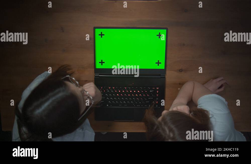 Two attractive young girls look at the green screen of the laptop Stock ...