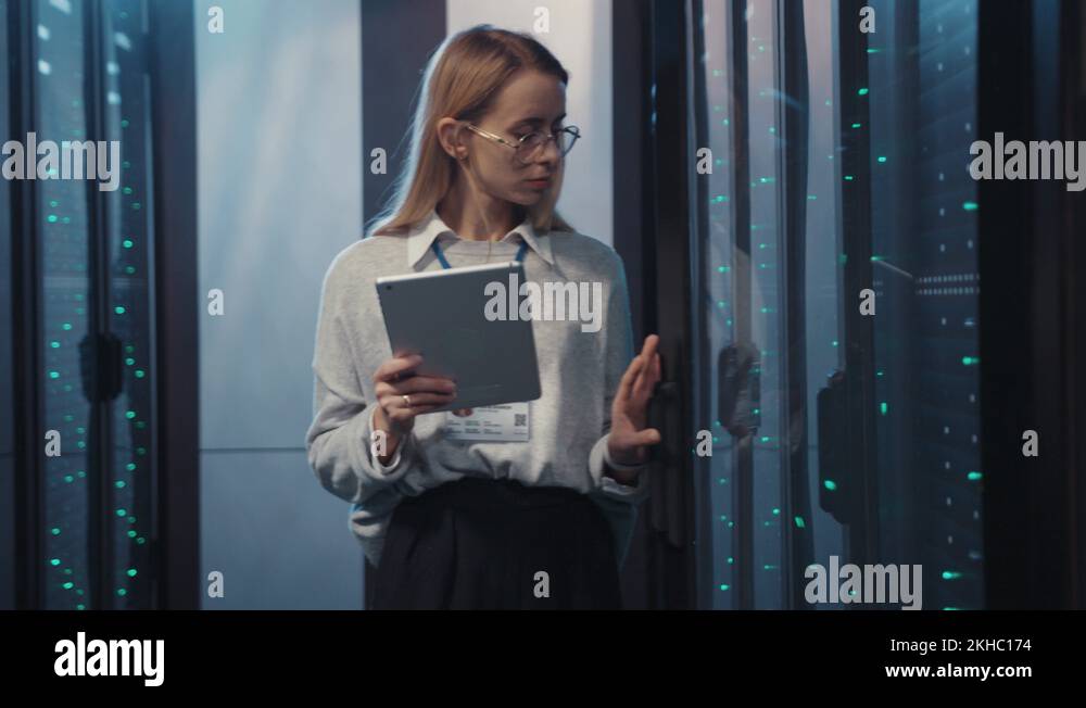 Female server technician using tablet inspecting rack server computers ...