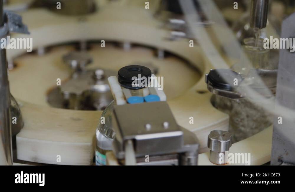 Pouring medicine on an assembly line into glass bottles for injection ...