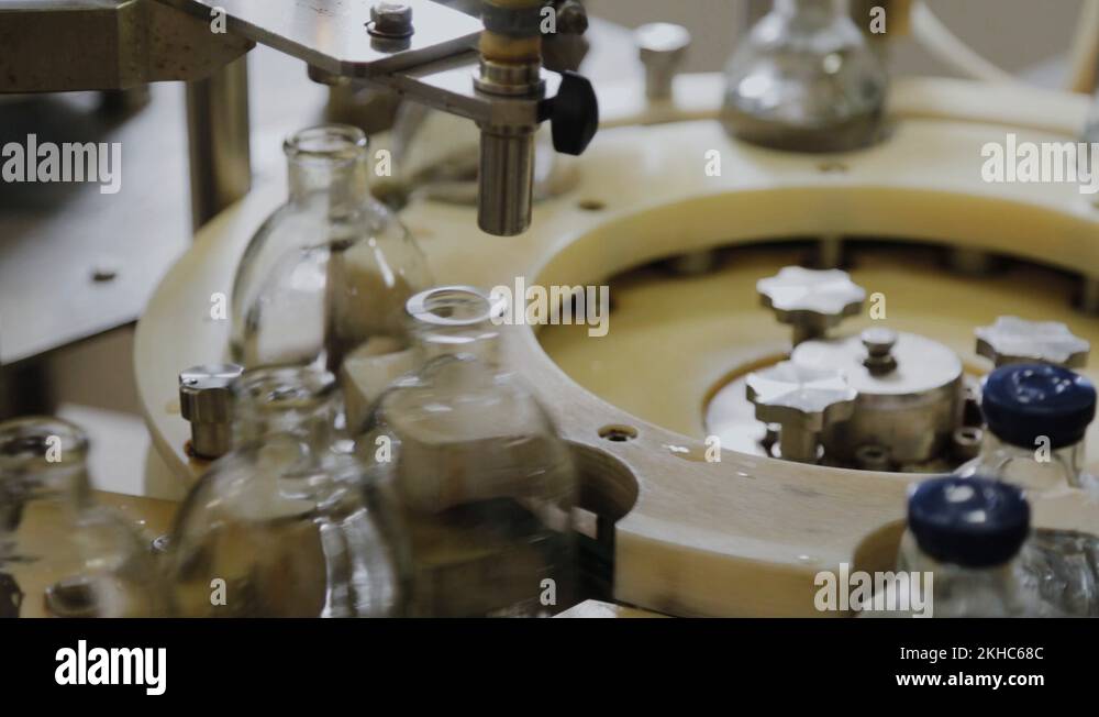 Pouring medicine on an assembly line into glass bottles for injection ...
