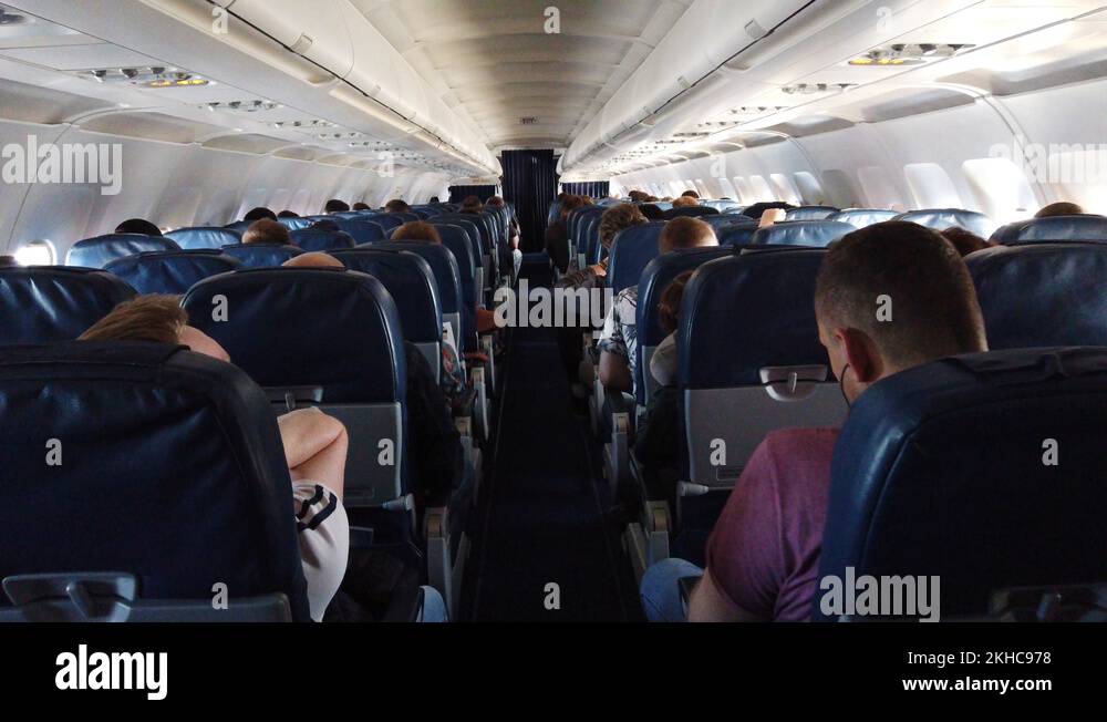 Economy class interior, aircraft cabin. Passengers sit in their seats ...