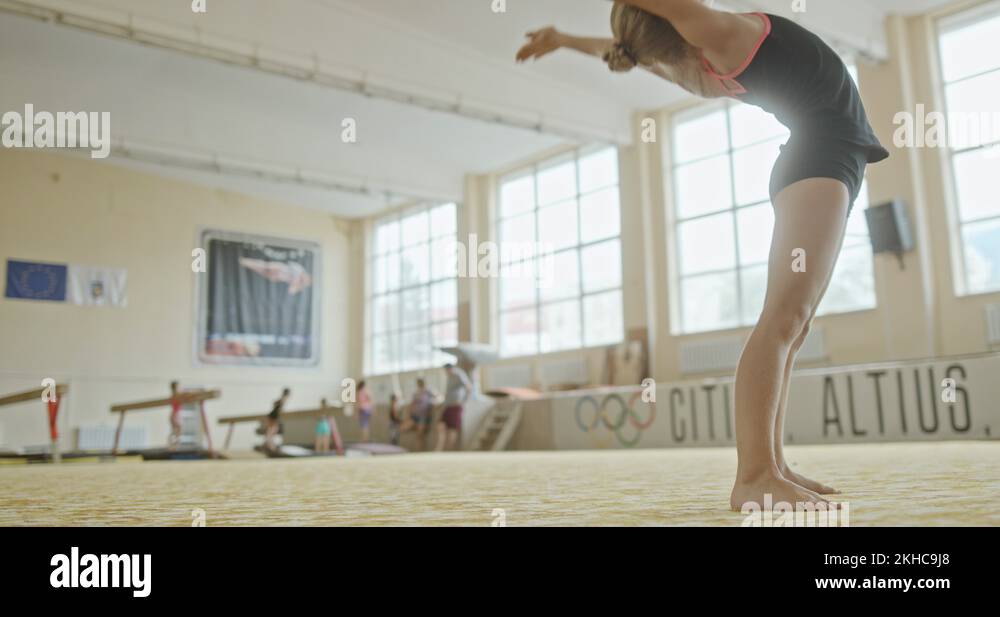 Agile supple young girl doing a back roll in a ballet studio on a ...
