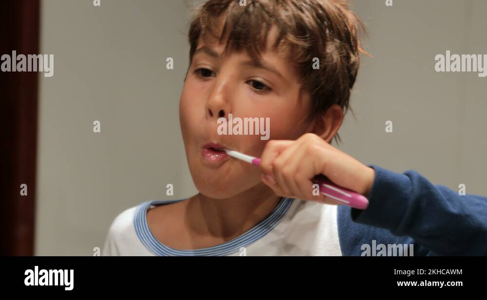 Child brushing teeth in front of mirror in 4K. Young boy brushes teeth ...