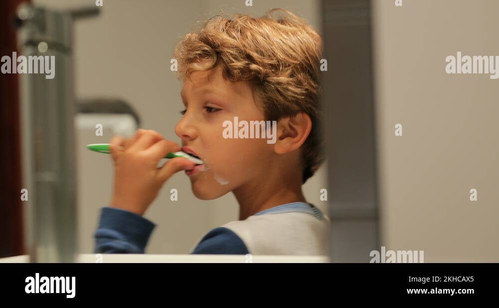 Child brushing teeth in front of mirror in 4K. Young boy brushes teeth ...