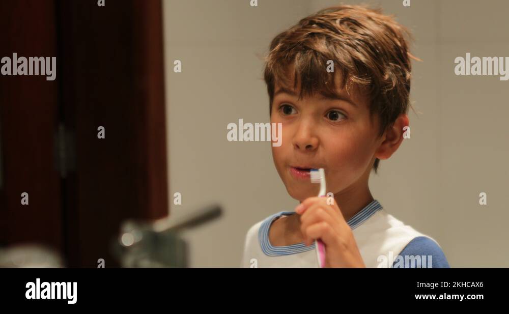 Child brushing teeth in front of mirror in 4K. Young boy brushes teeth ...