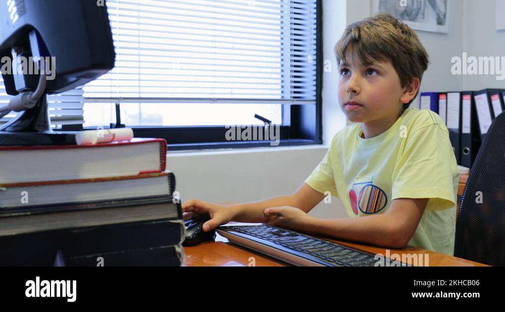 Child in front of computer at office desk. Young boy using father desk ...