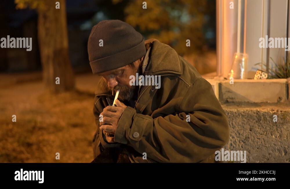 Homeless sick man smoking cigarette on the street at night Stock Video ...