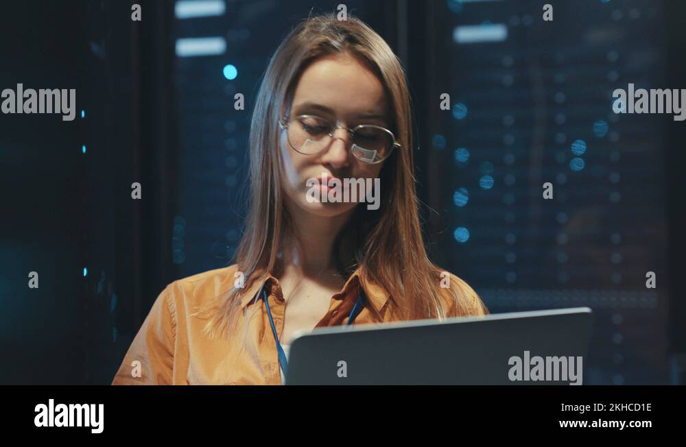 Smart female IT administrator working in operational server room ...