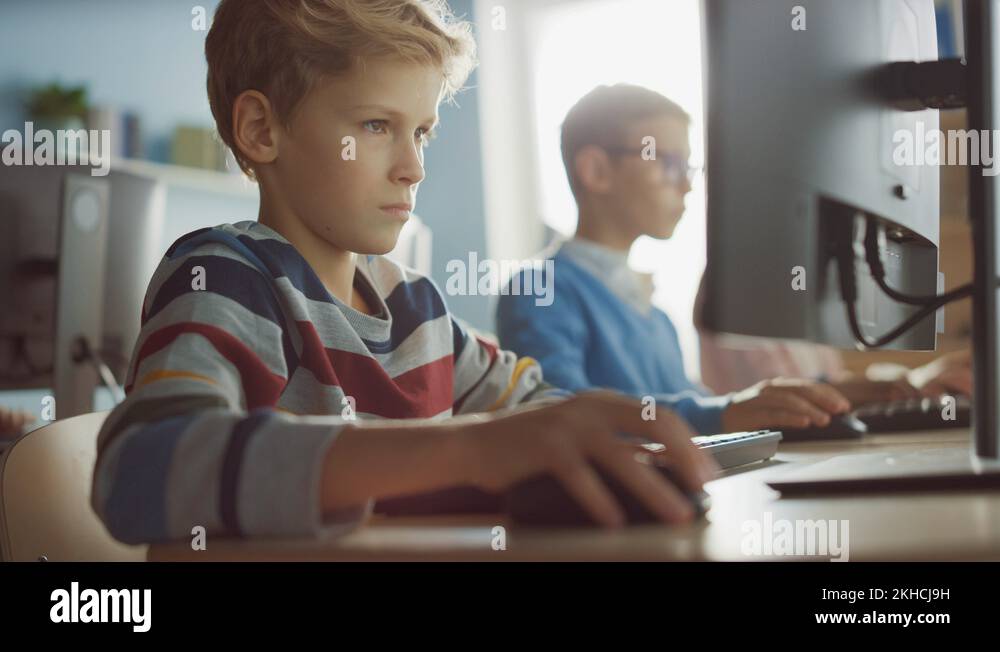 Elementary School Computer Science Classroom: Smart Little Boy Uses PC ...