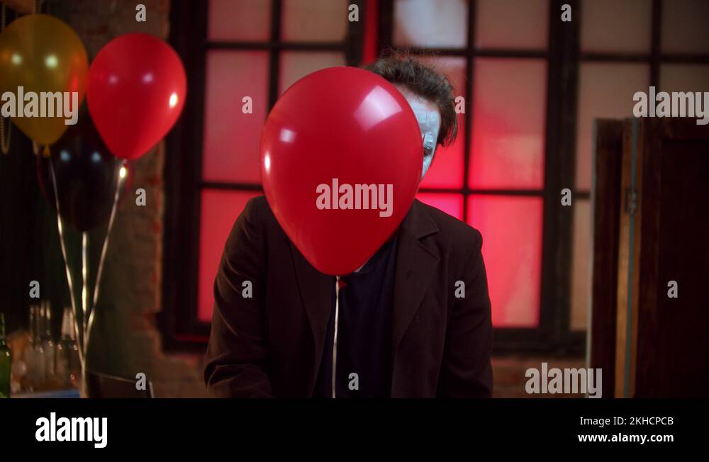 A scary clown slightly peeking out from the red balloon and creepy ...