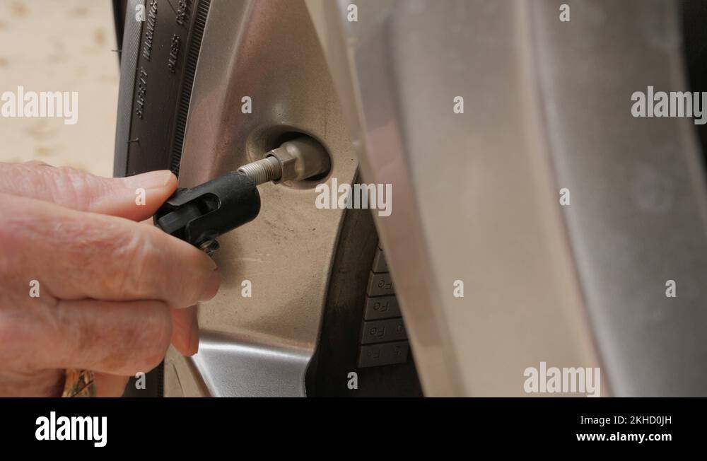 Mechanic inflating and checking automotive tire for proper inflation ...