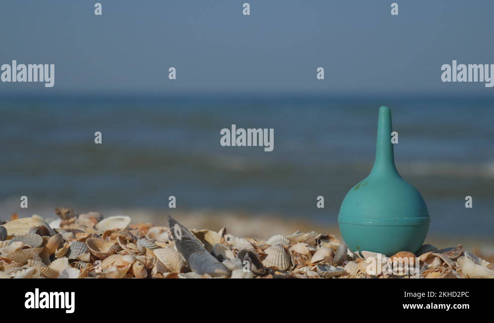 rubber, pear-shaped syringe is standing shells on the seashore. place ...