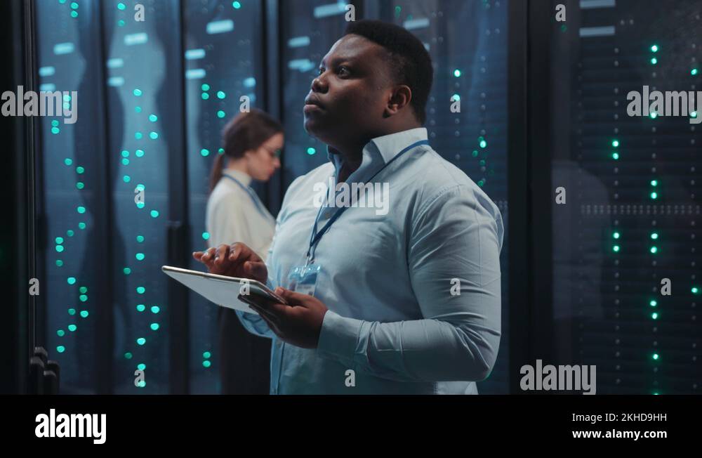 African technician in data center checking working server rack in ...